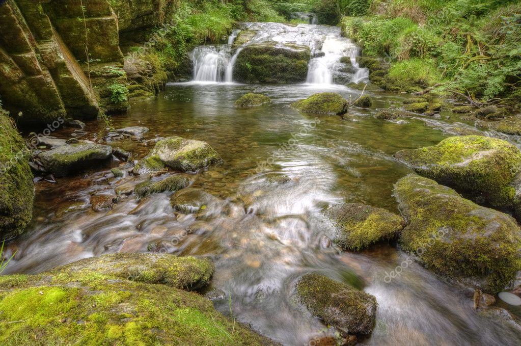 Stunning waterfall flowing over rocks through lush green forest — Stock ...