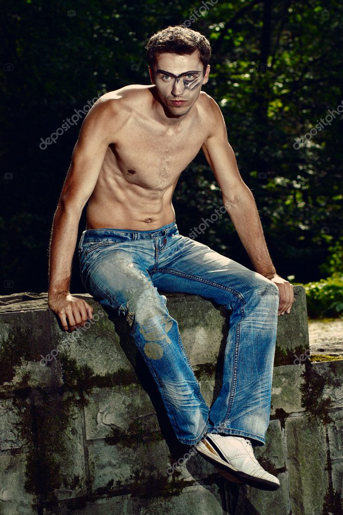 Handsome man in jeans trousers sitting on the wall — Stock Photo ...
